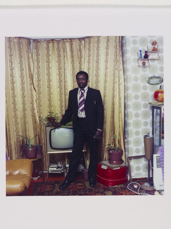 Untitled [A well fully clad man photographed standing by his television ...