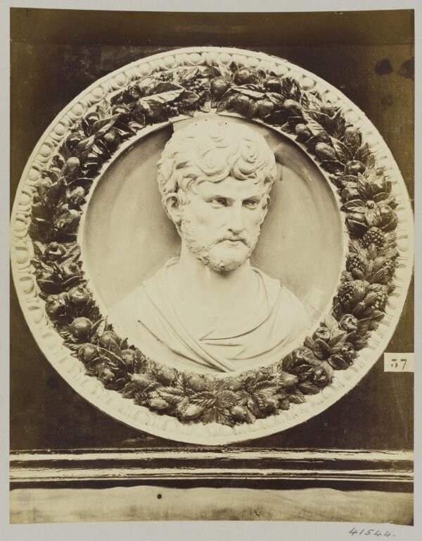 Circular bas-relief white portrait bust on blue ground surrounded by a ...